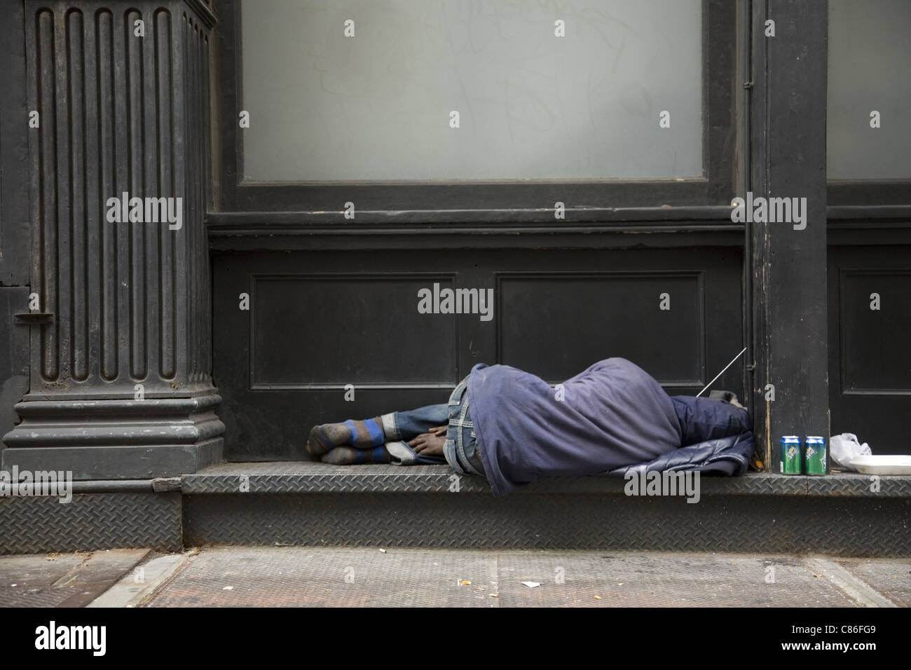 Homeless man sleeps on a building ledge in Manhattan Stock Photo - Alamy