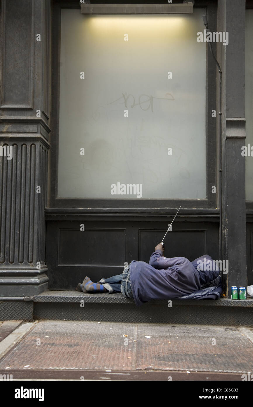 Homeless man adjusts his portable radio in his impromptu bed on 18th St ...