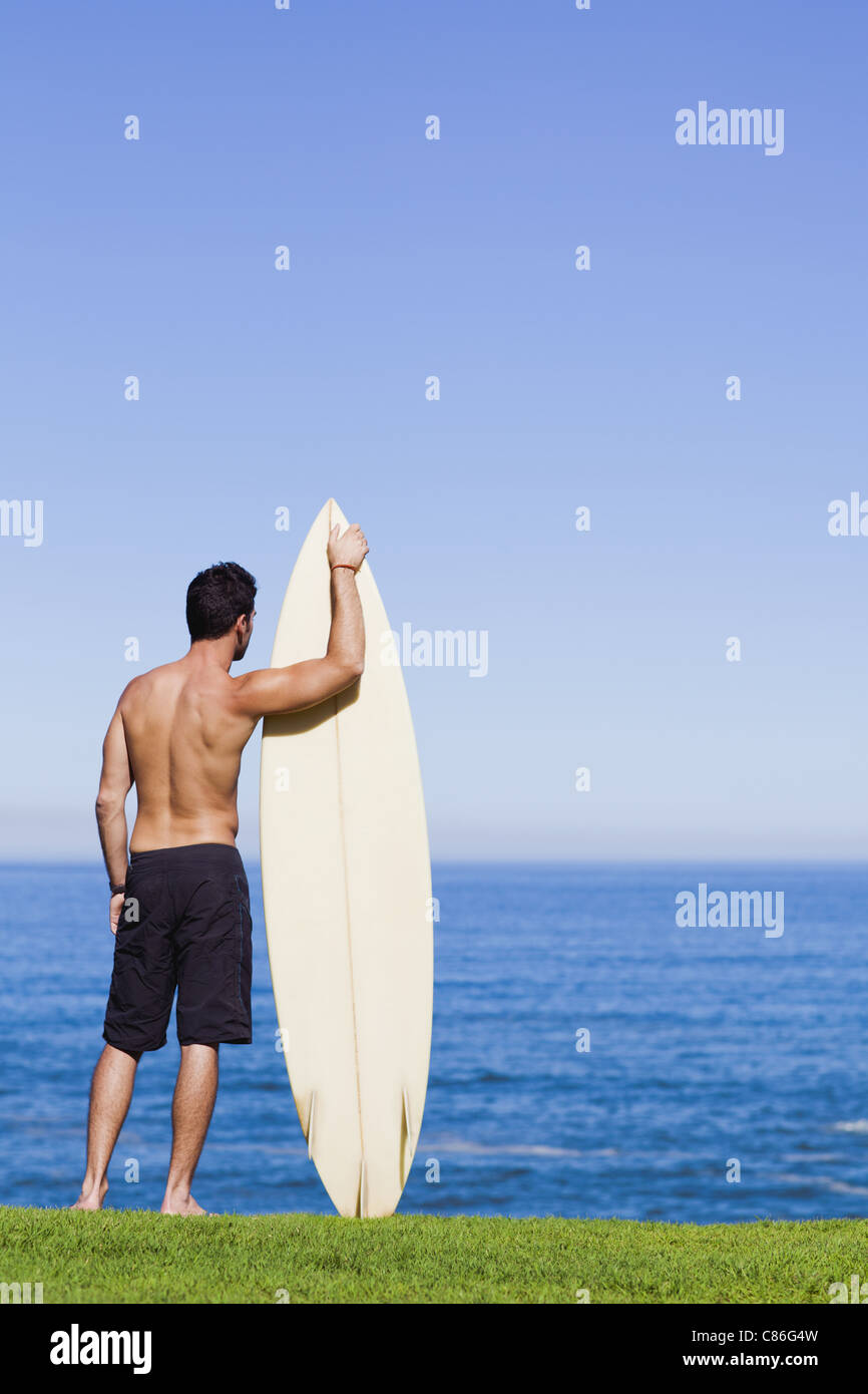 Man holding surfboard by ocean Stock Photo - Alamy
