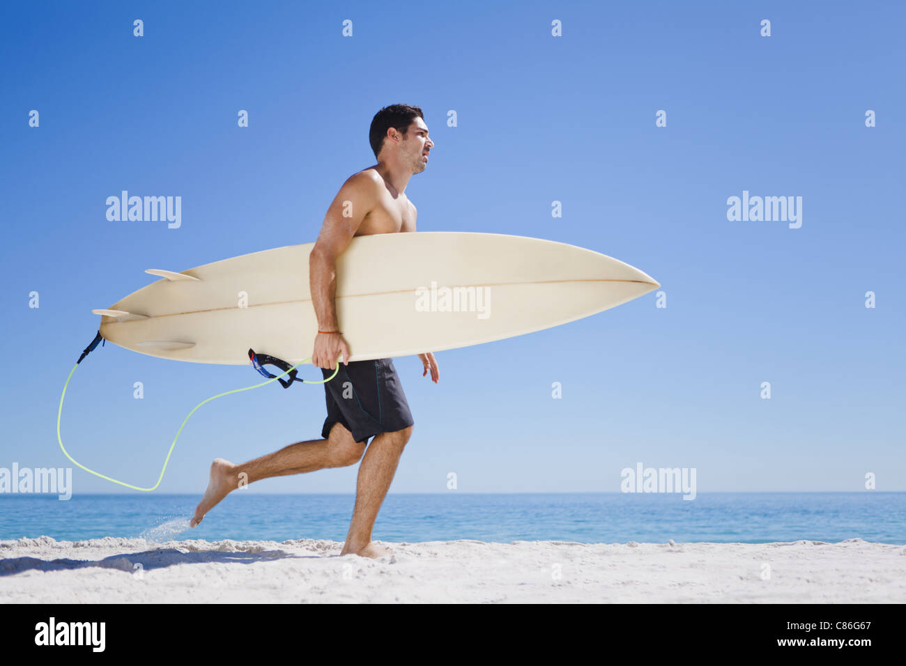 Man carrying surfboard on beach Stock Photo - Alamy