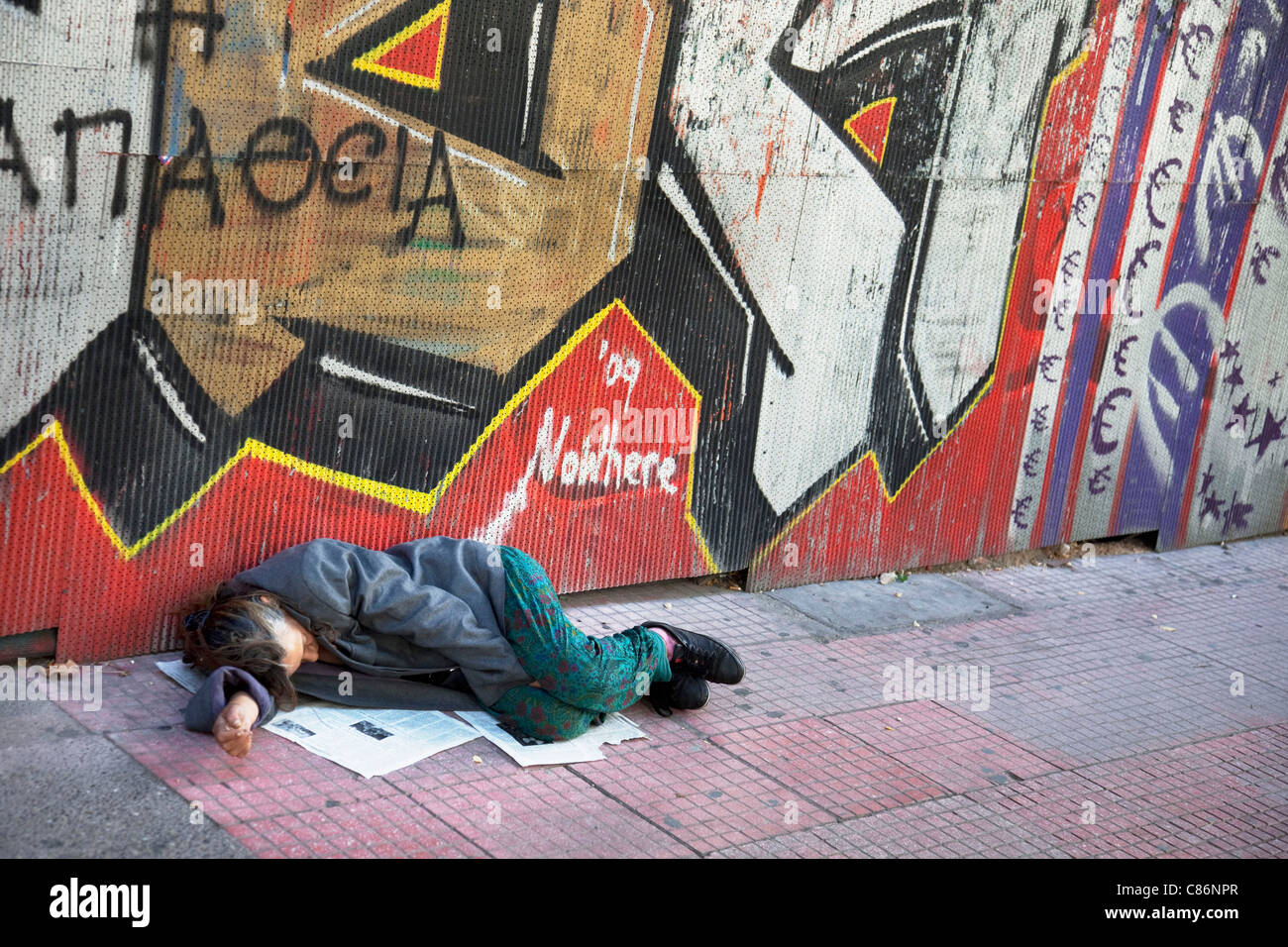 People walk past a homeless woman sleeping on the streets. The gap ...