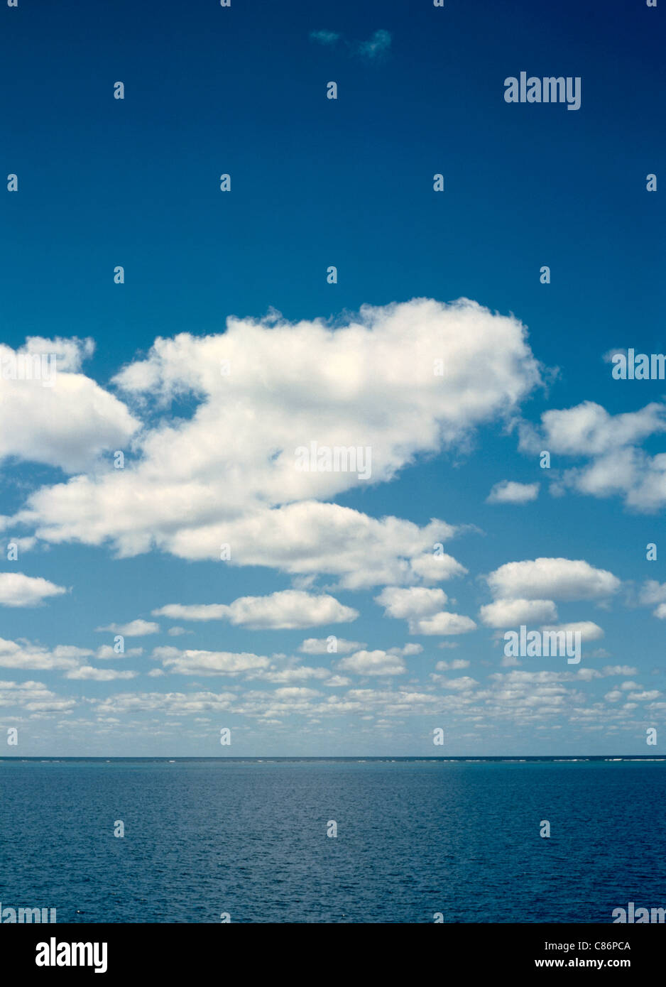 View of blue sky with white cumulus clouds over the ocean horizon ...