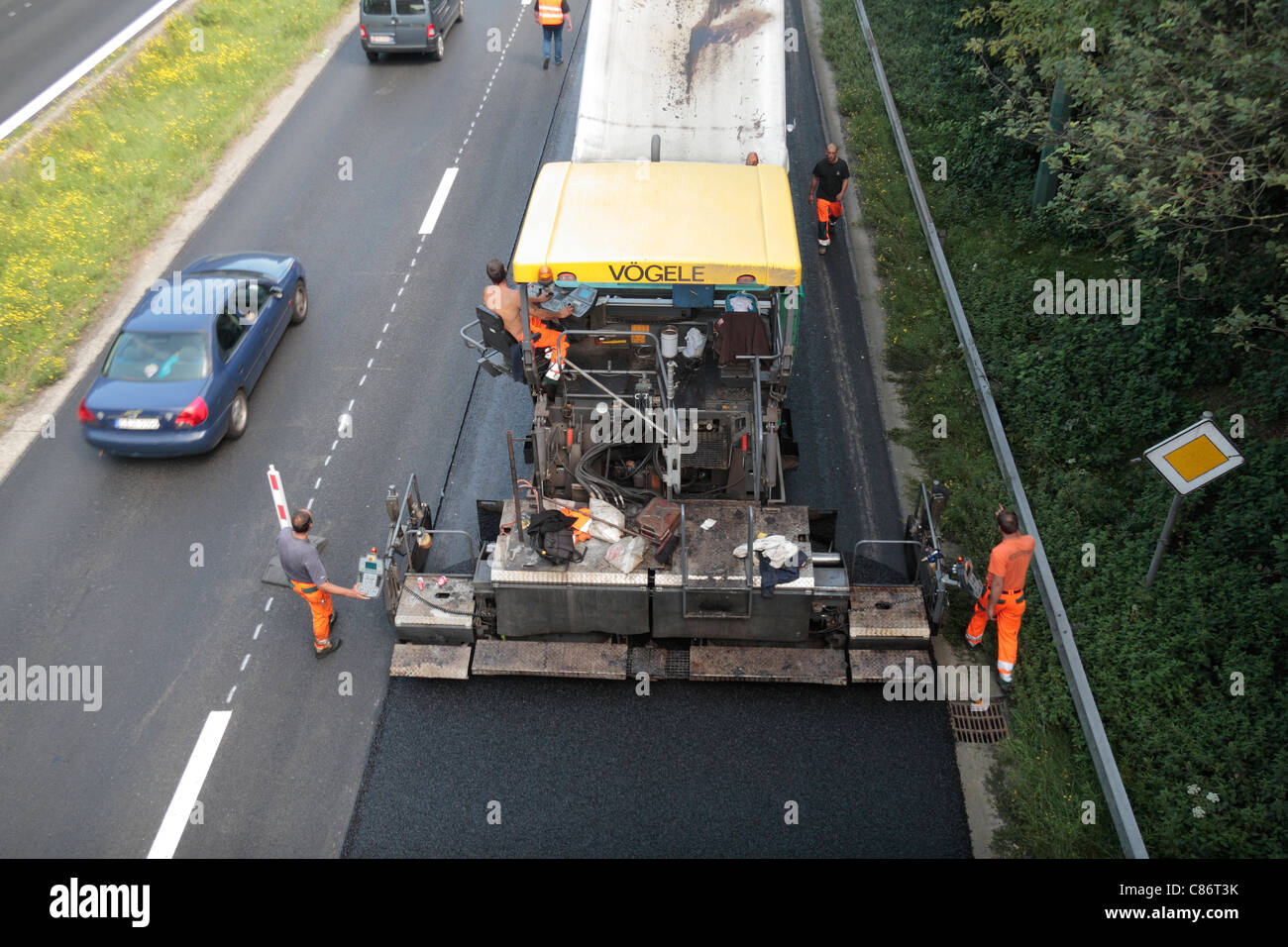 A sub-surface layer of bitumen being applied by paver machine on a main ...