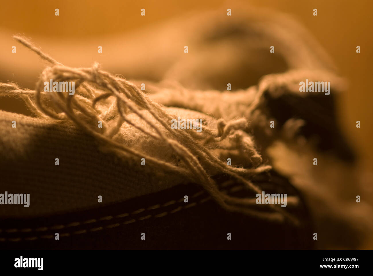 Frayed strands of canvas denim string that were formerly part of a shoe ...