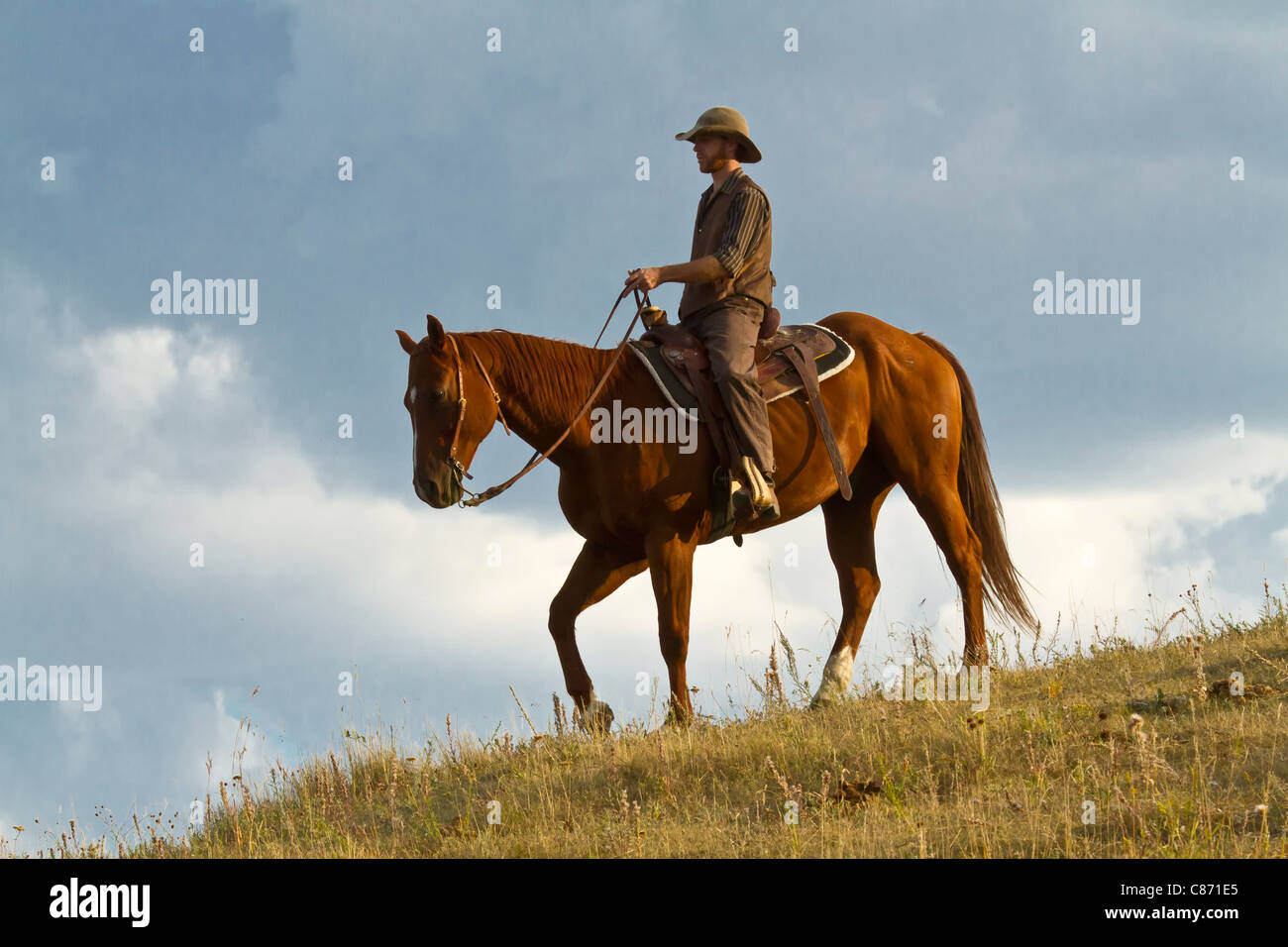 Lone cowboy riding a brown horse on a grassy hill in South Dakota Stock ...
