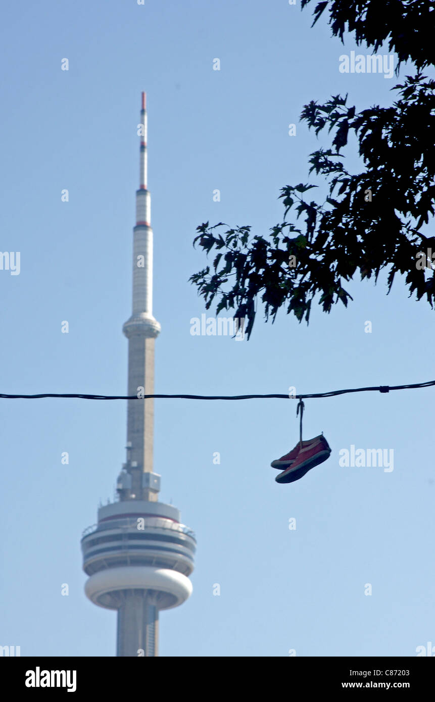 A pair of shoes hanging over a wires with the CN Tower in the ...