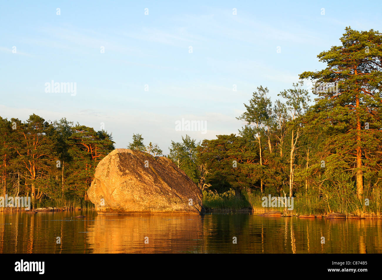 Big rock in a Swedish lake glowing in the light of the setting sun ...