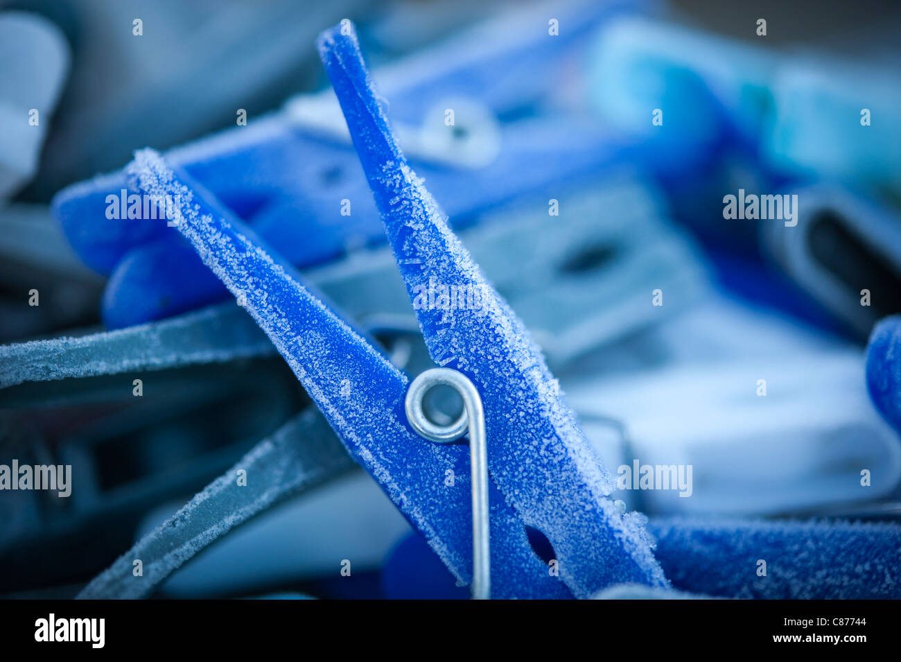 Frozen blue clothes pegs covered in ice Stock Photo - Alamy