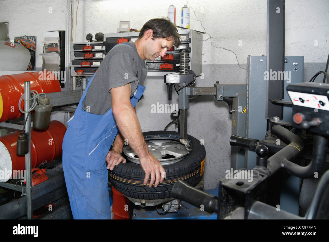 Germany, Ebenhausen, Mechatronic technician working on tyre in car ...
