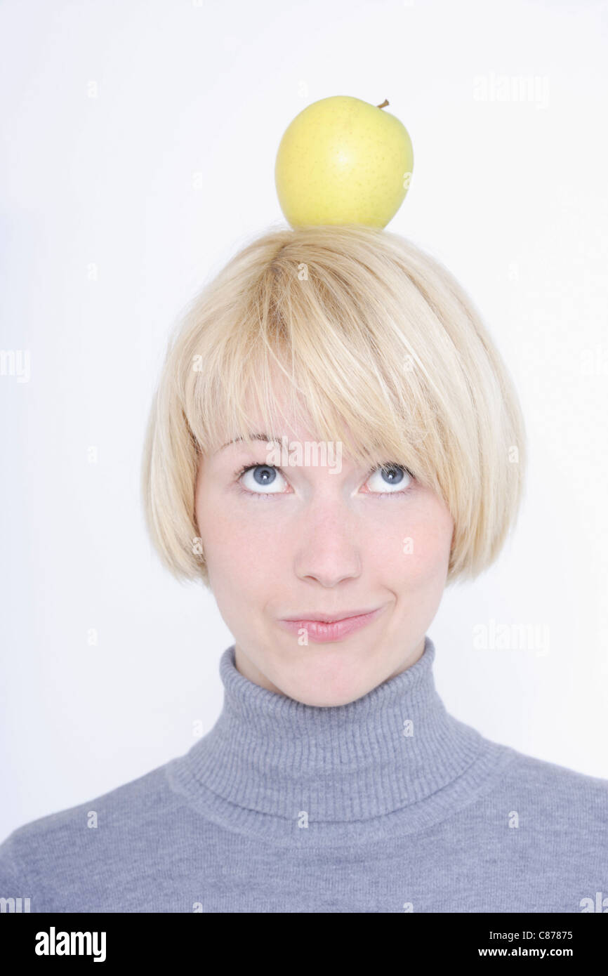 Close up of young woman balancing fruit on head against white ...