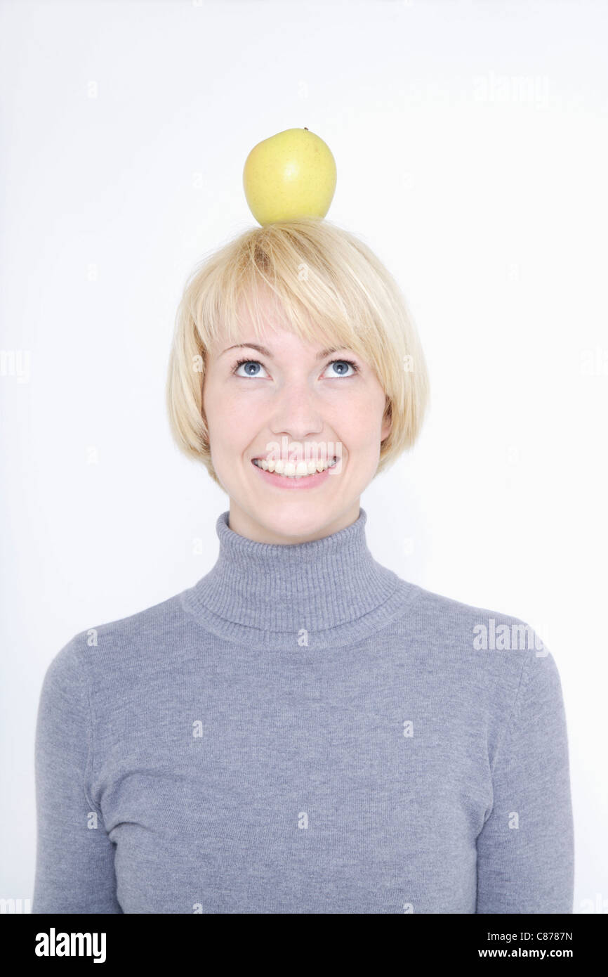 Close up of young woman balancing fruit on head against white ...