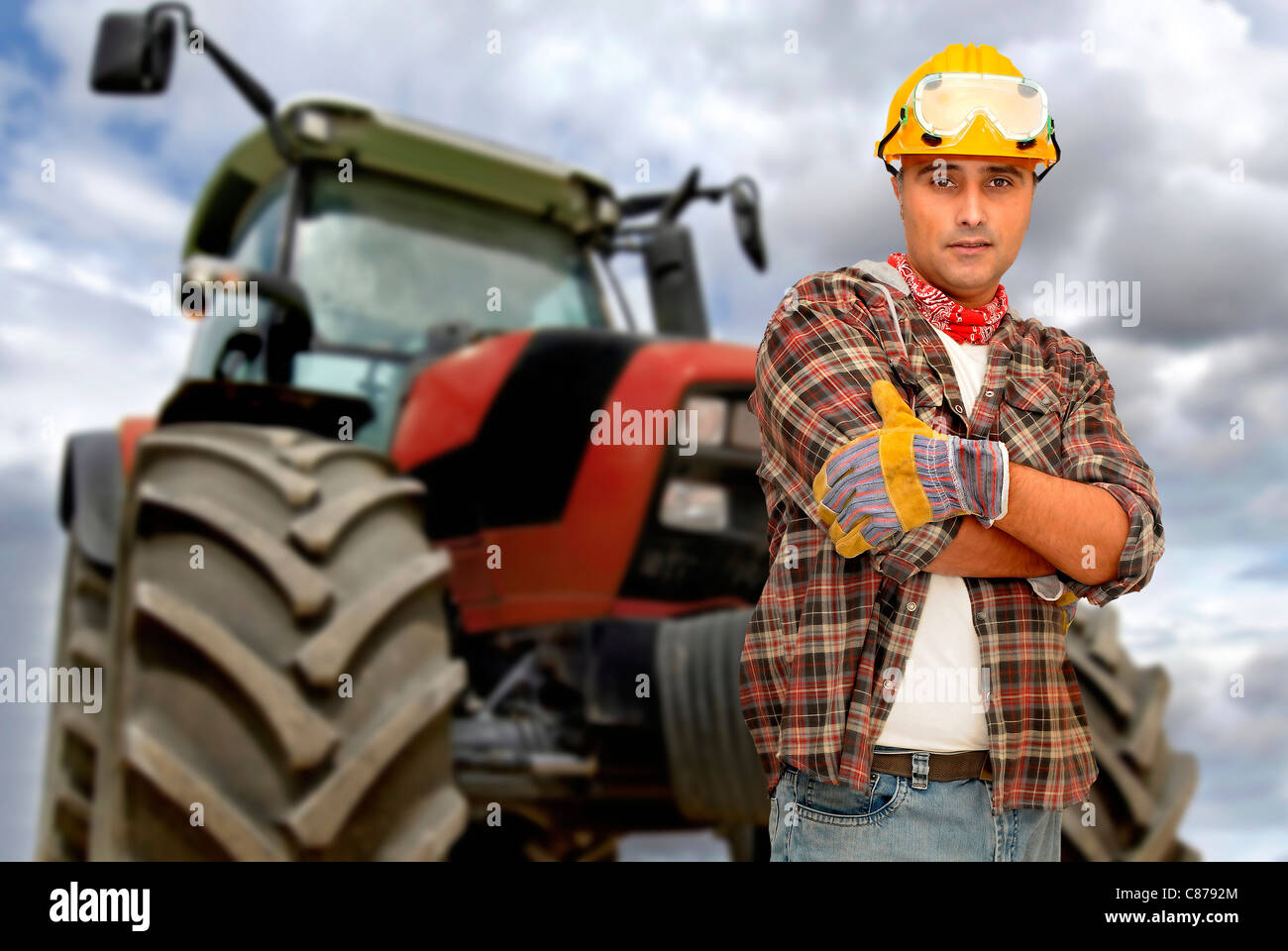 Worker with tractor on the background Stock Photo - Alamy