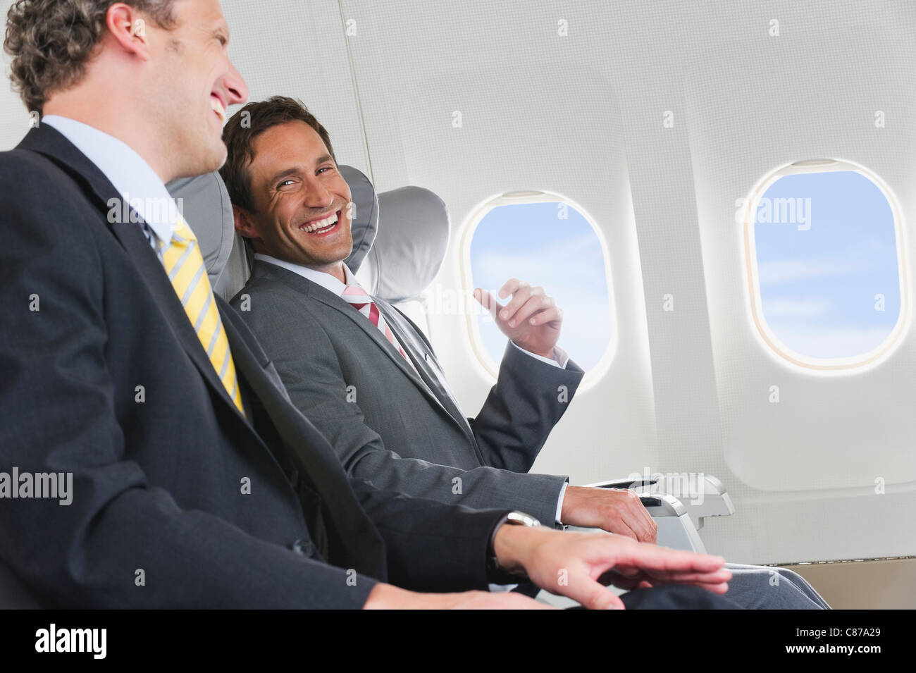 Two business men laughing on airplane hi-res stock photography and ...
