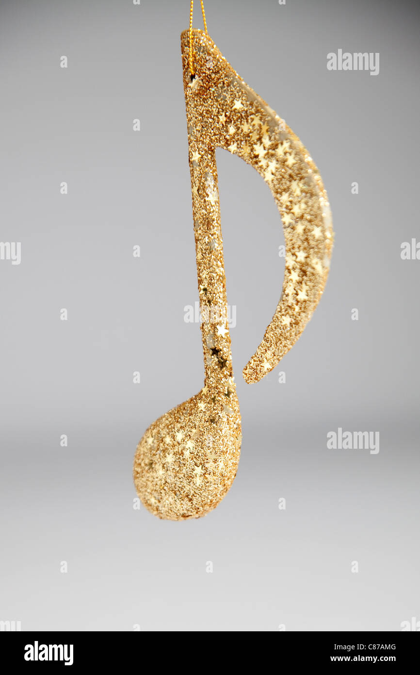 A gold sparkley music note, against a plain grey background Stock Photo ...