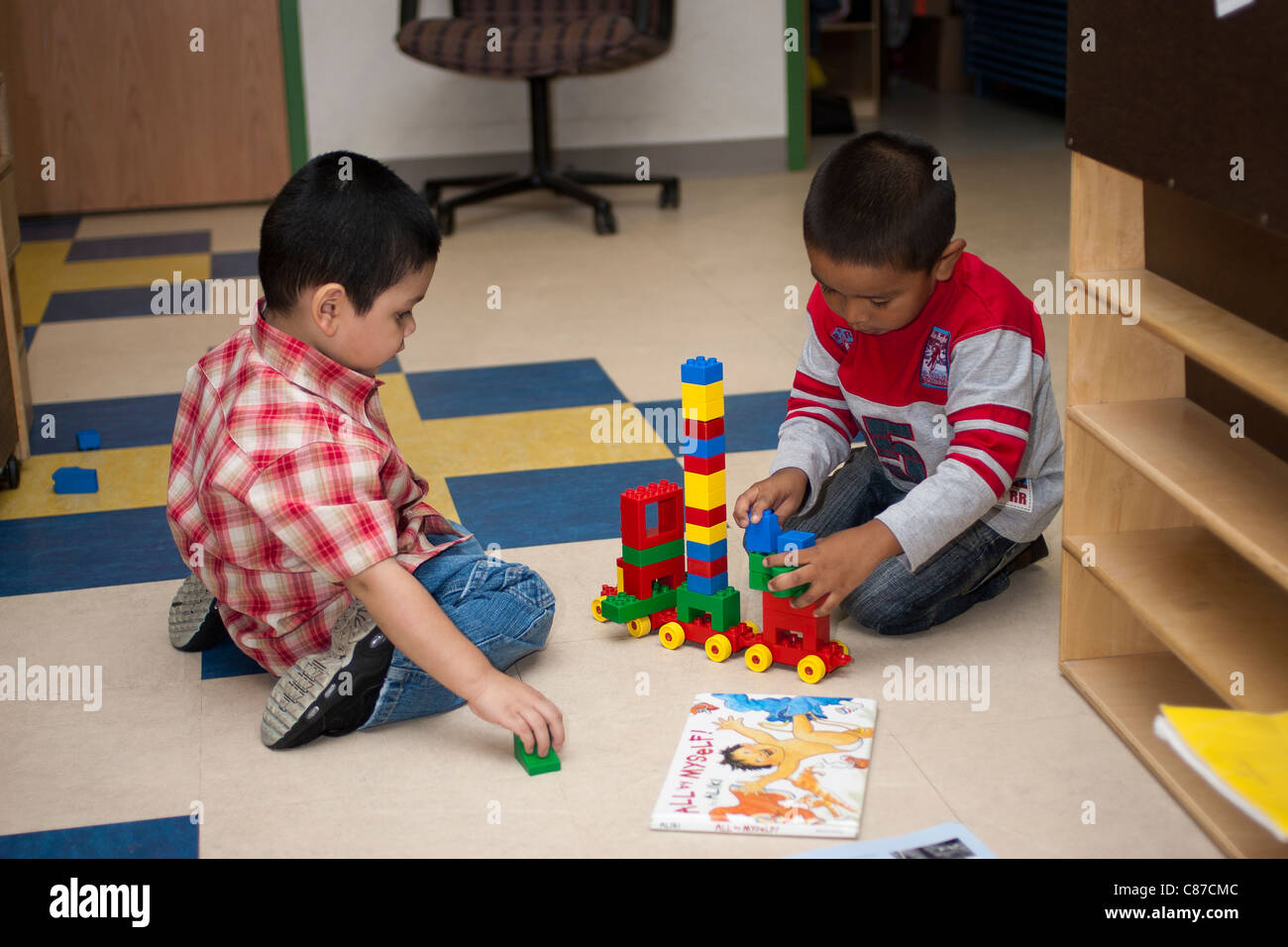 Two 4 year old preschool boys playing with lego's on the floor in the ...