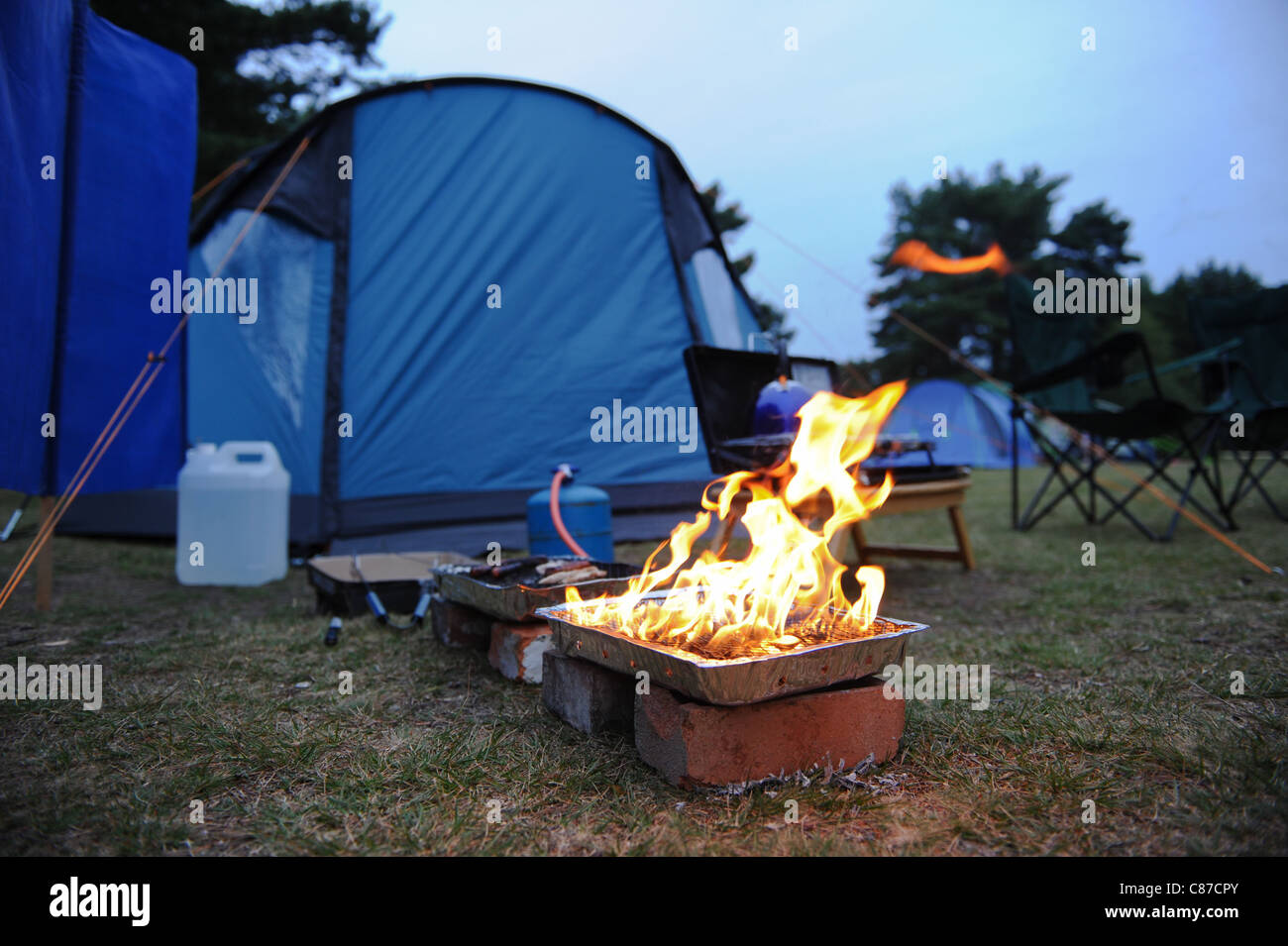 a barbecue lit next to a tent with various cooking equipment around to ...
