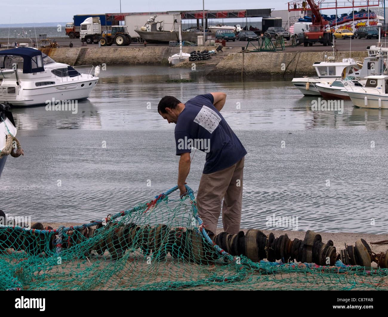 Horizontal portrait of Fisherman mending nets in the harbour work ...