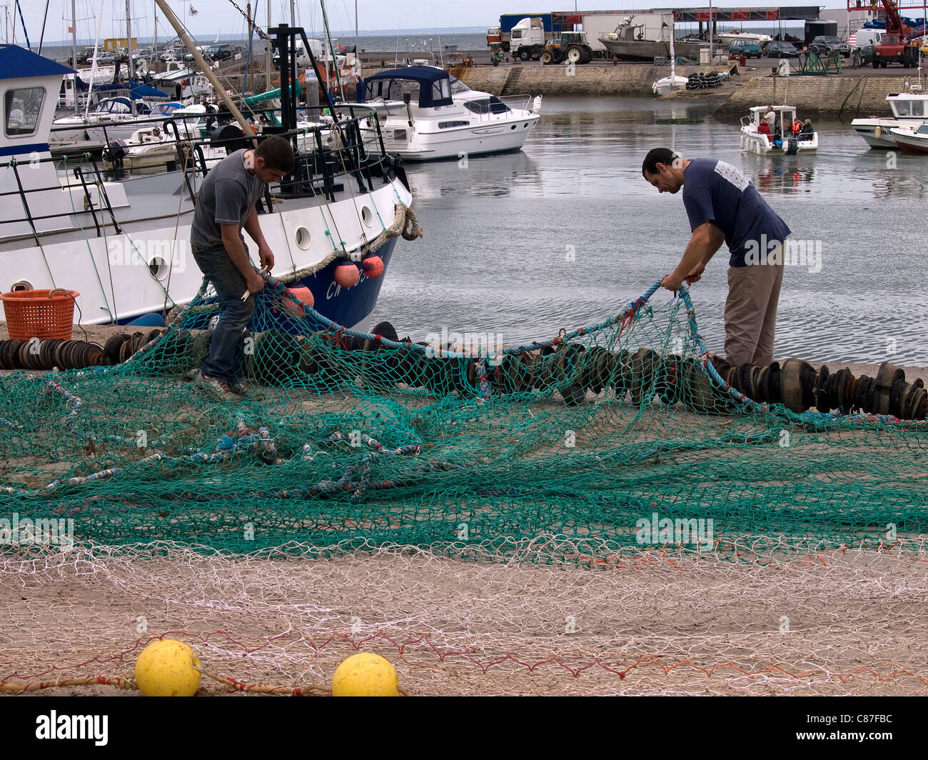 Horizontal portrait of Fishermen mending nets in the harbour, Normandie ...