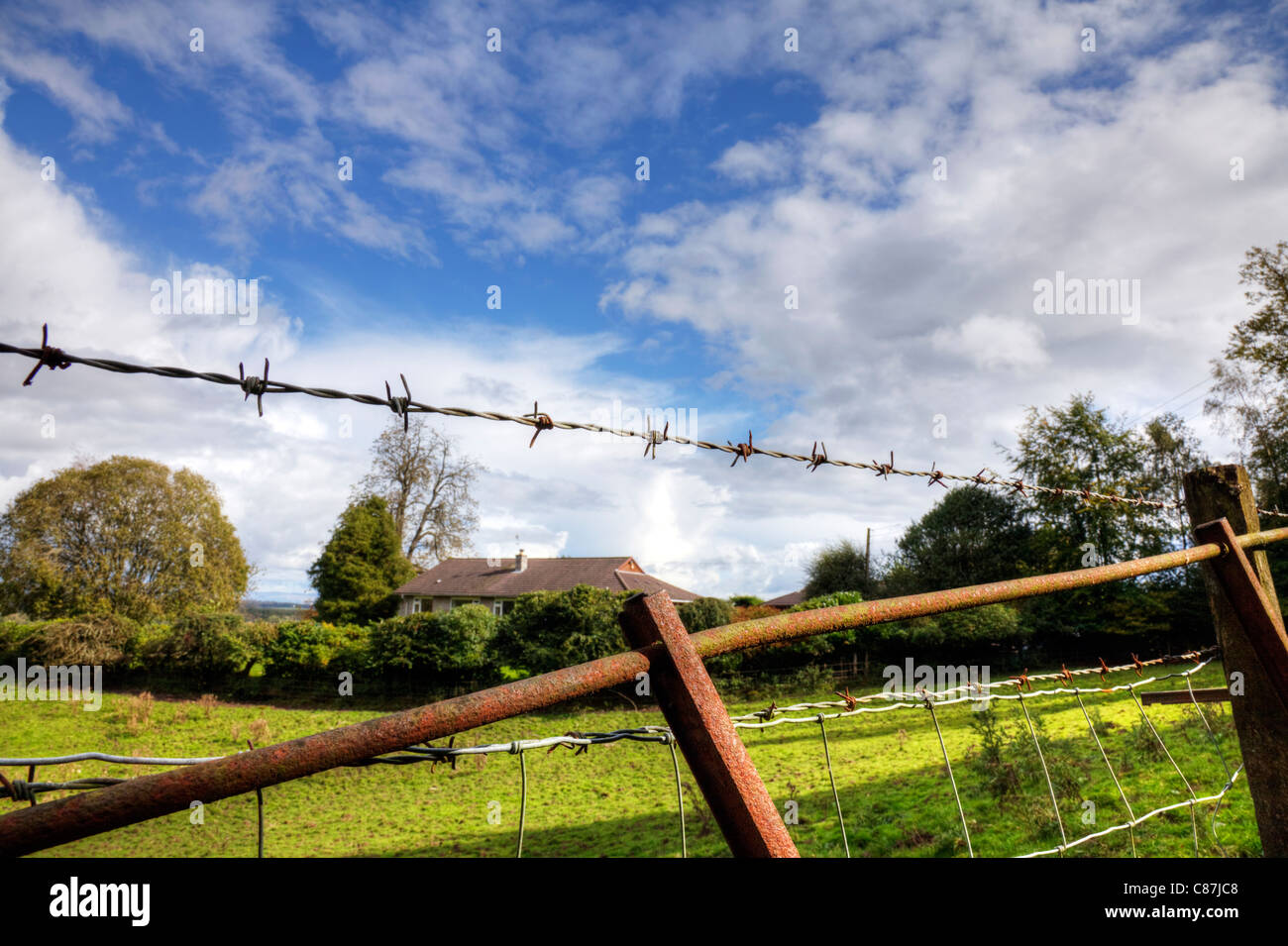 Close detail of a barb, barbed wire fence above an old rusty gate in ...