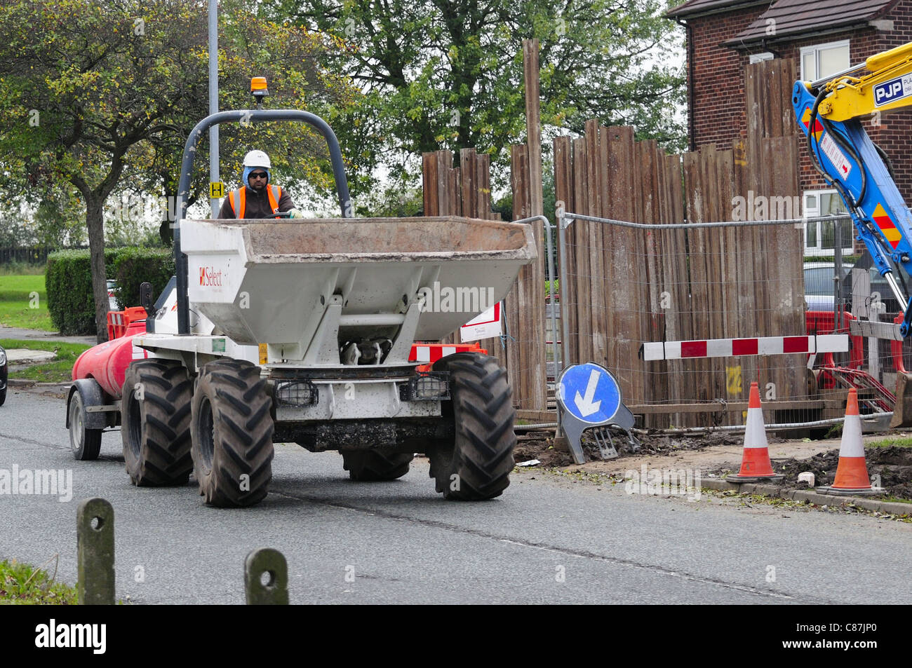 Tipper truck towing small liquid bowser container past roadworks Stock ...