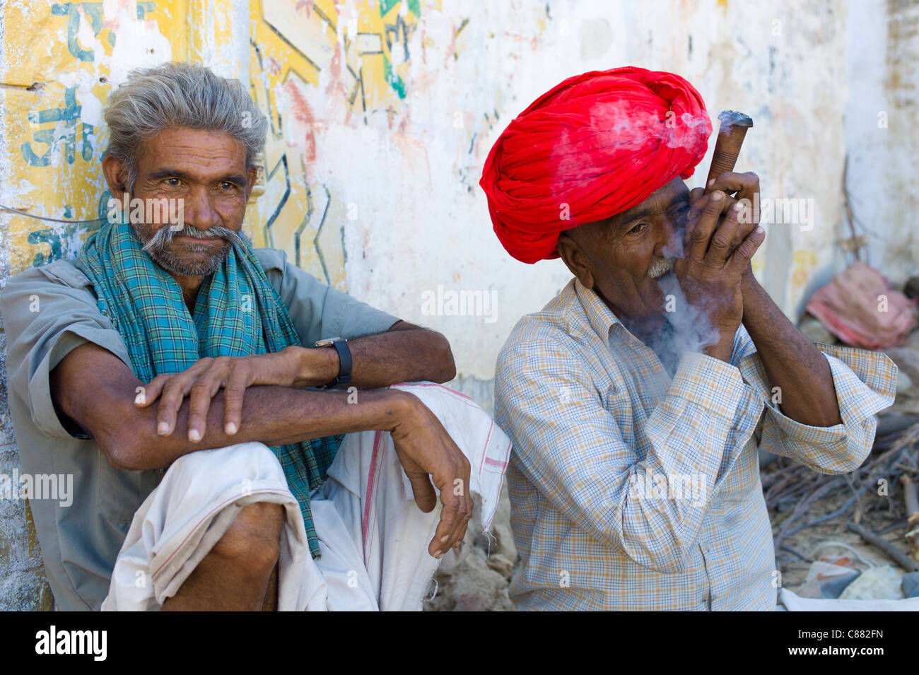 Indian man in traditional clothing smokes clay pipe while sitting with ...