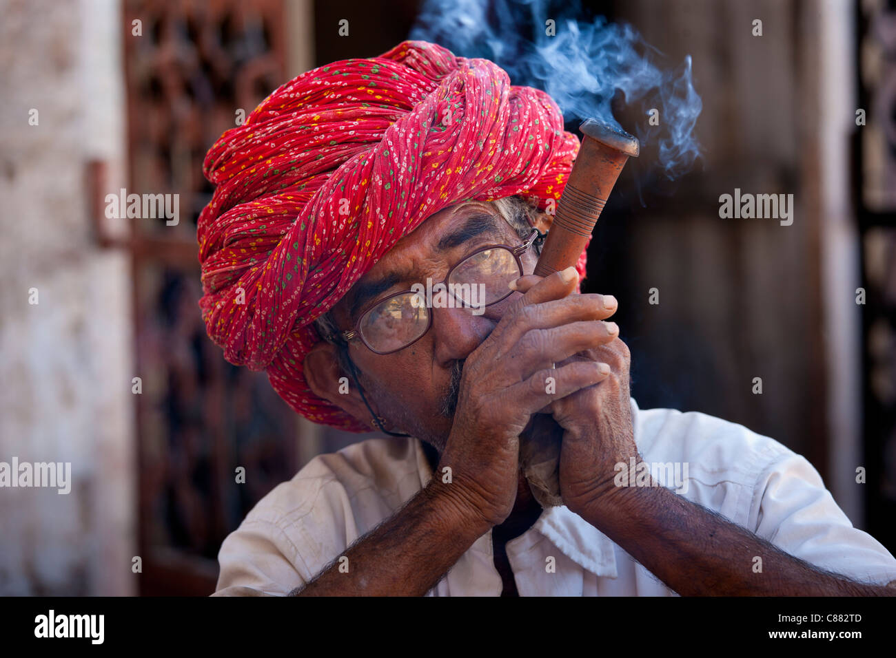 Indian man wearing Rajasthani turban smokes traditional clay pipe in ...