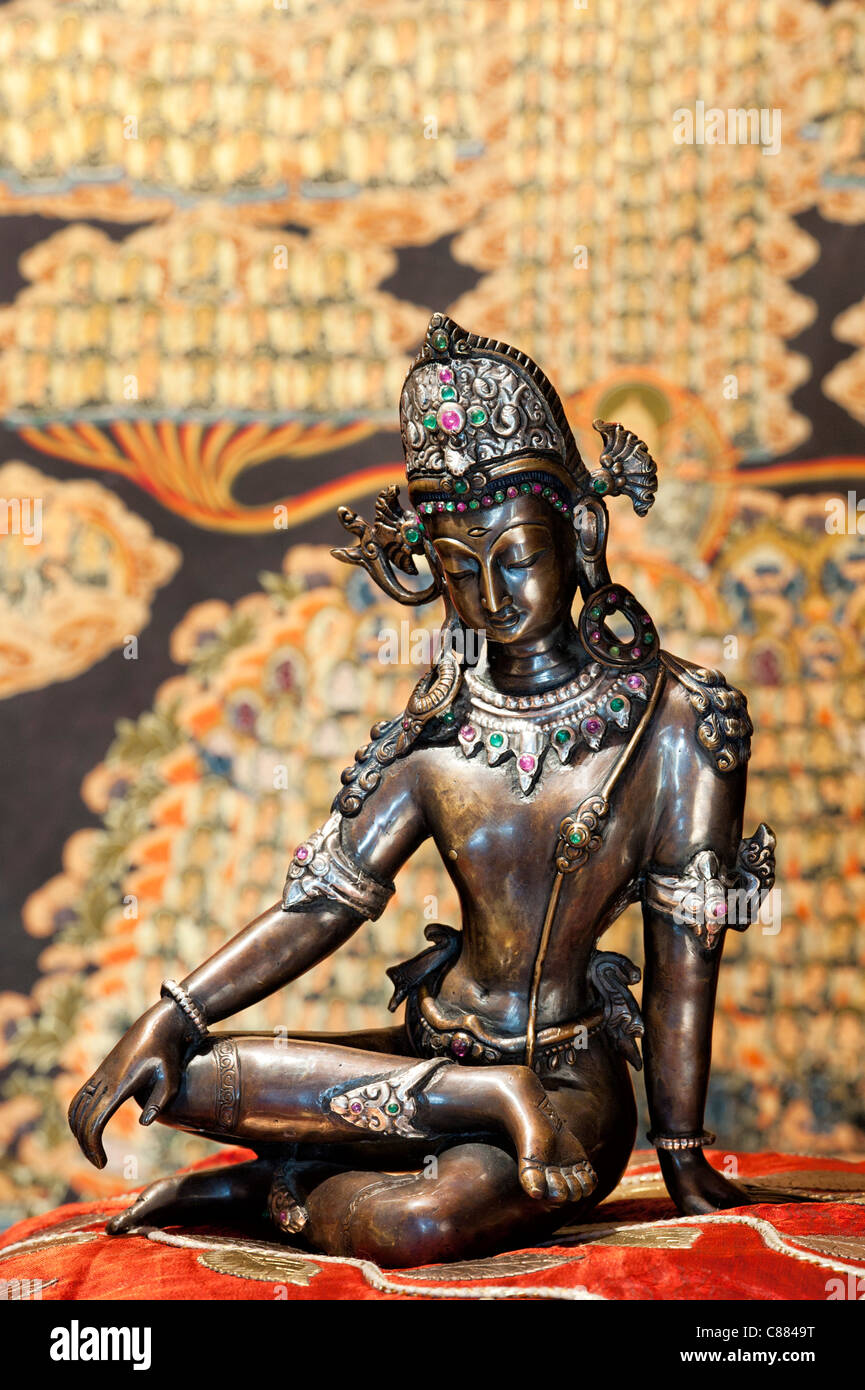 Female Indian Goddess deity statue in front of a Tibetan Buddhist Thangka / Tanka painting Stock ...