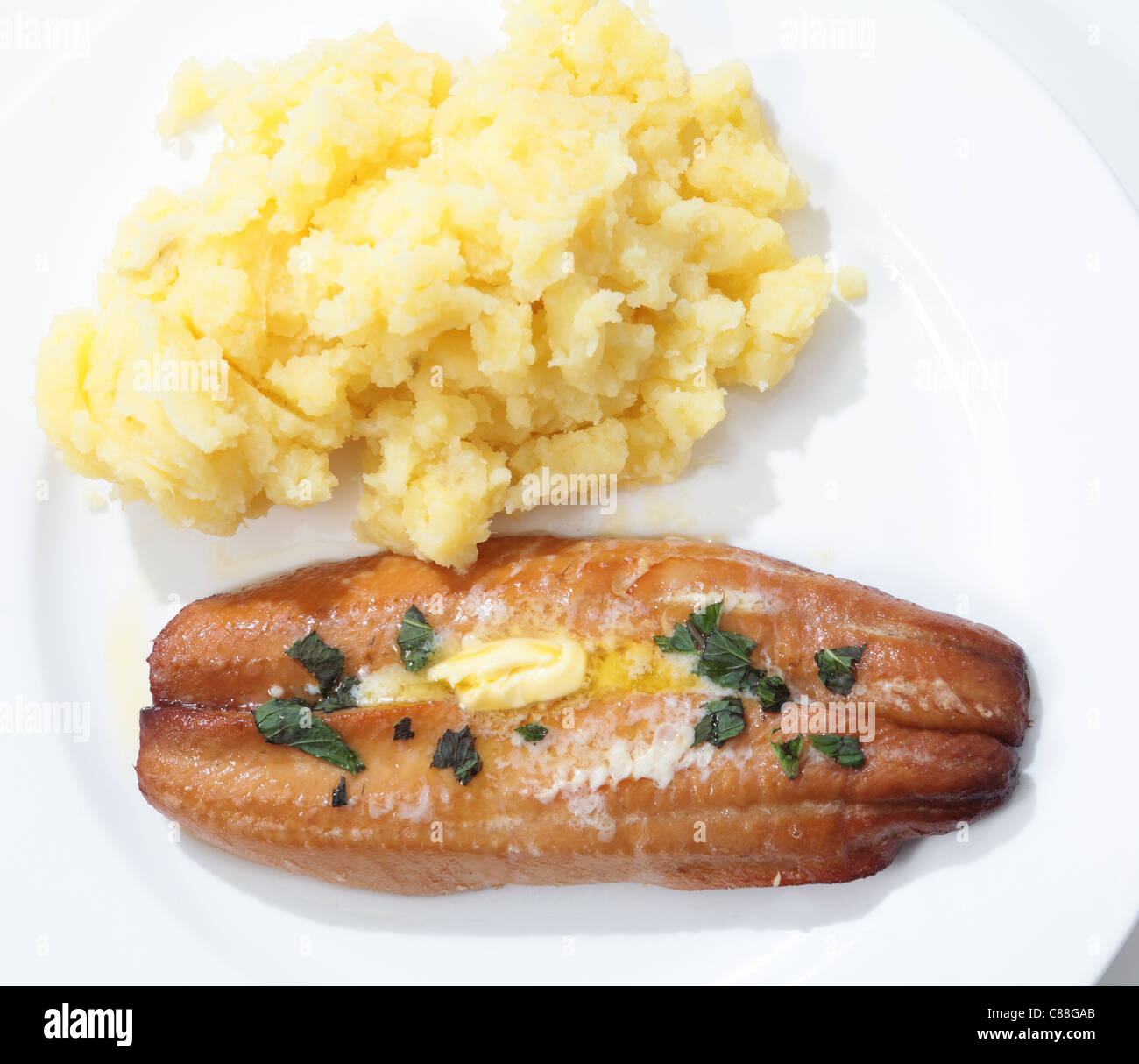Top view of a grilled kipper (smoked herring) garnished with butter and ...