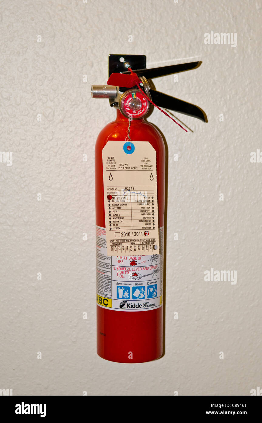 Red portable home fire extinguisher mounted on wall Stock Photo - Alamy