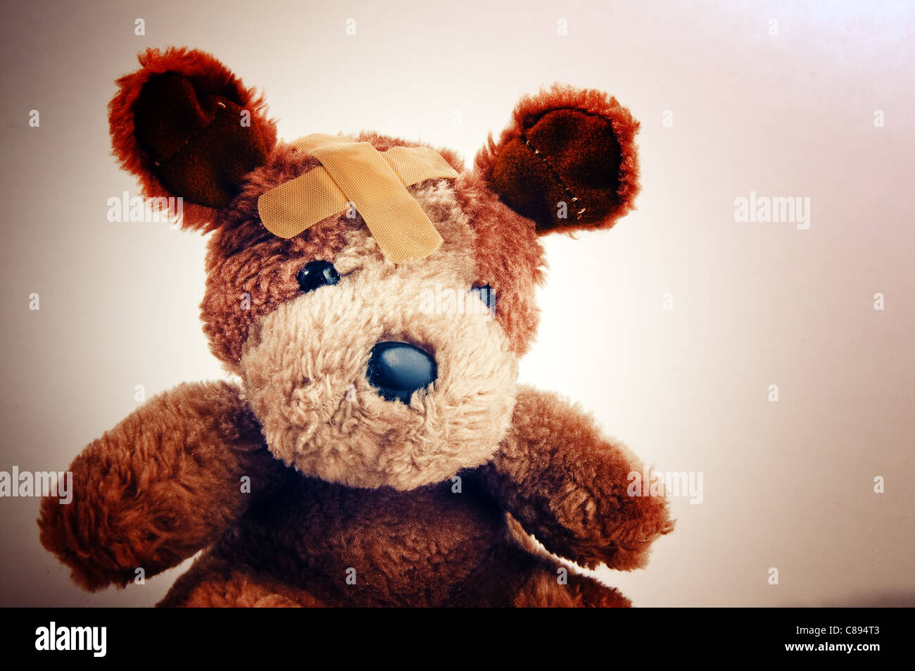 Cute little teddy bear with plaster on his head over a white background ...