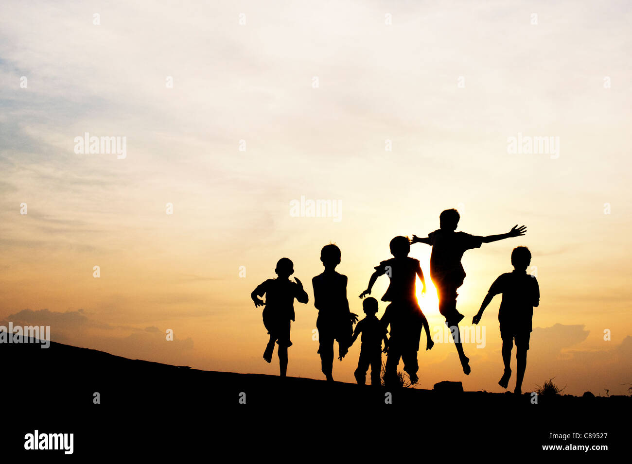Silhouette of young Indian boys running and jumping against at sunset ...