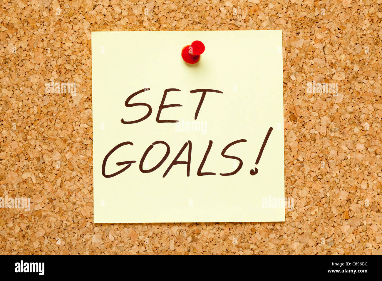 SET GOALS! written on an yellow sticky note on an office cork bulletin ...