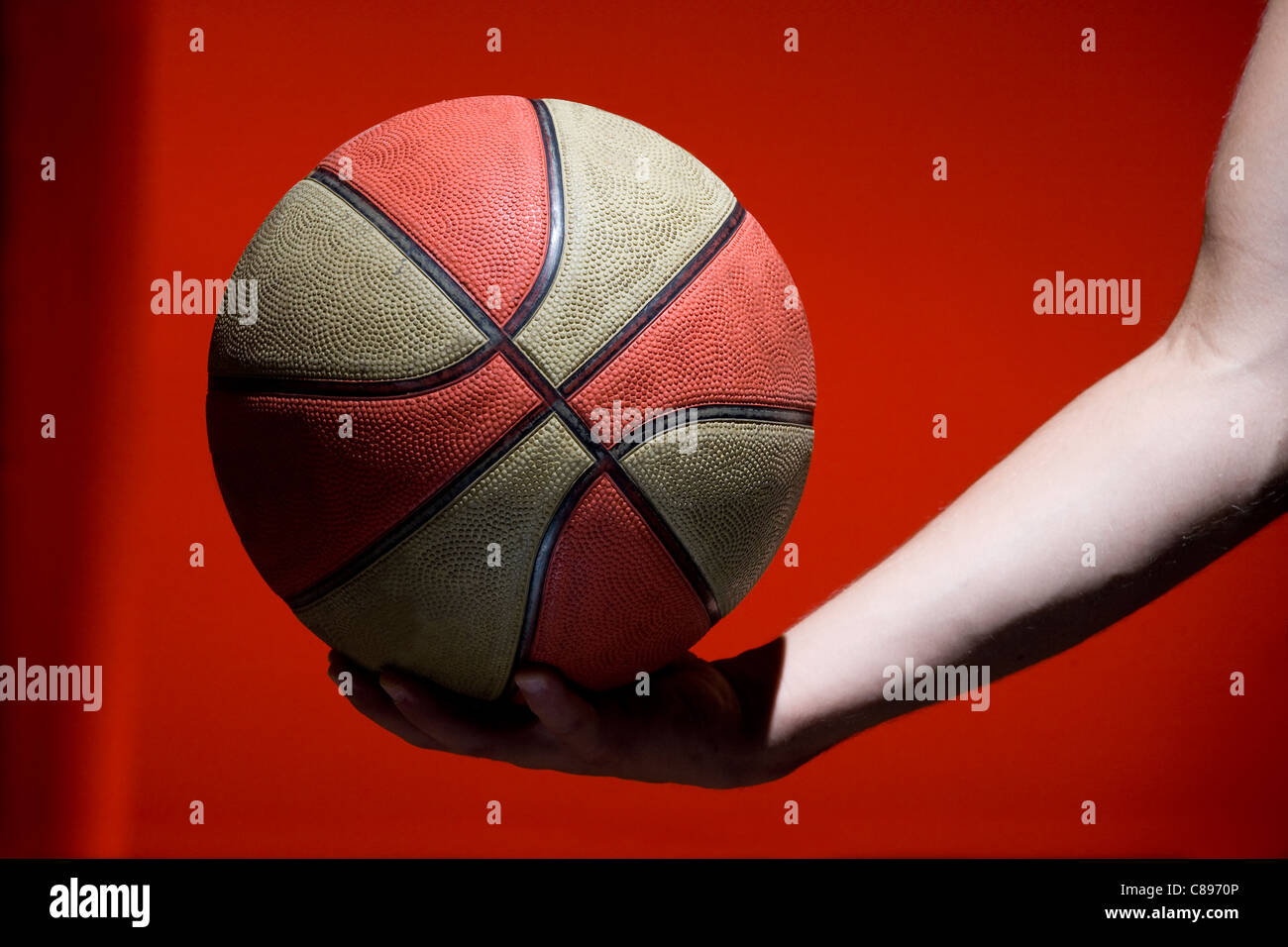 Basketball ball in hand isolated on red background Stock Photo - Alamy