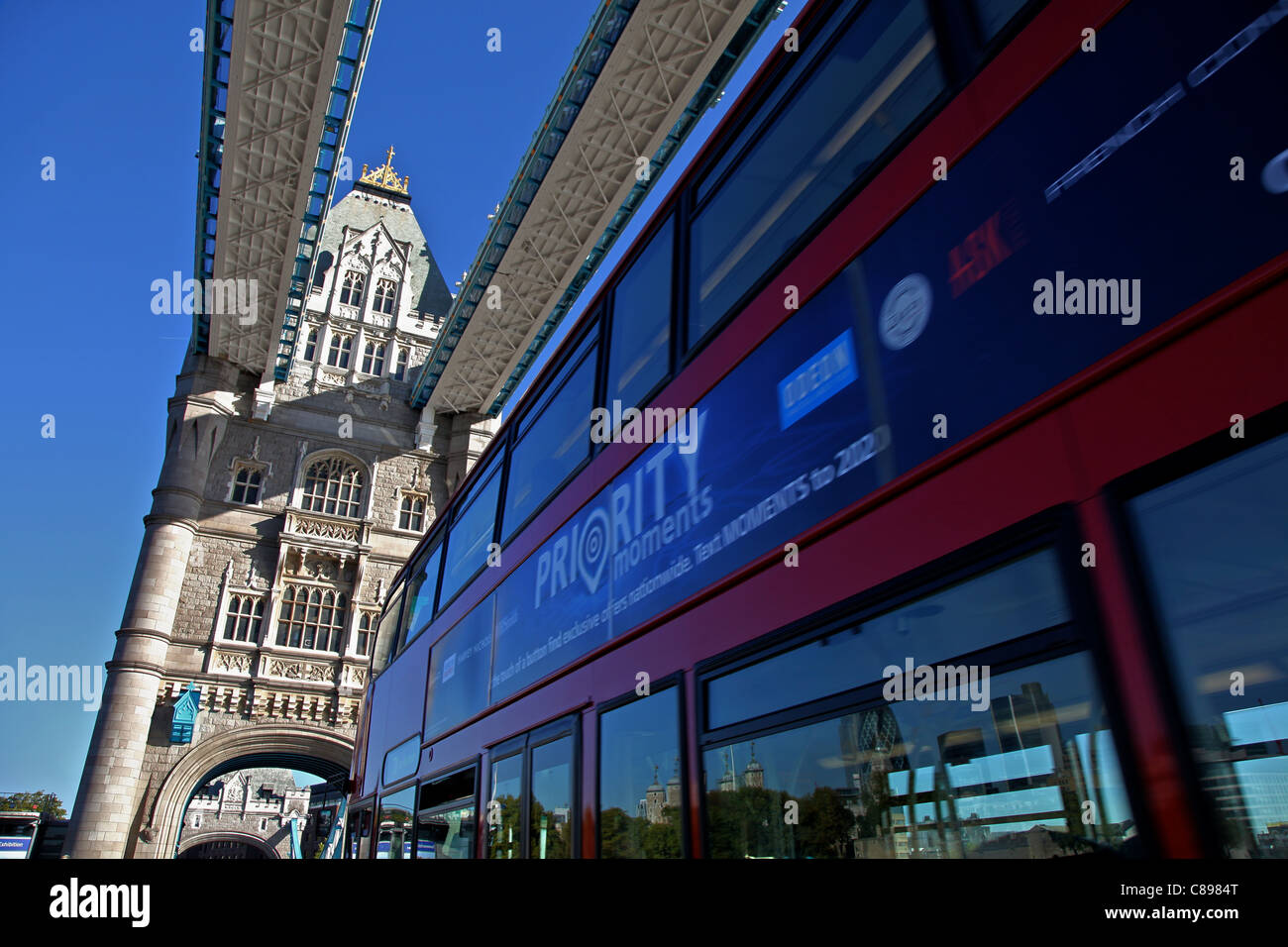 A double-decker red bus passing on the Tower Bridge with The City of ...