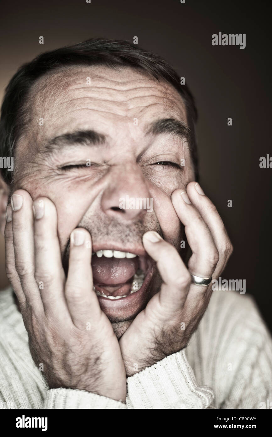 Close up of mature man making funny faces against black background ...