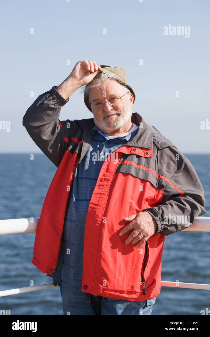 Senior man holding his hat in wind Stock Photo - Alamy