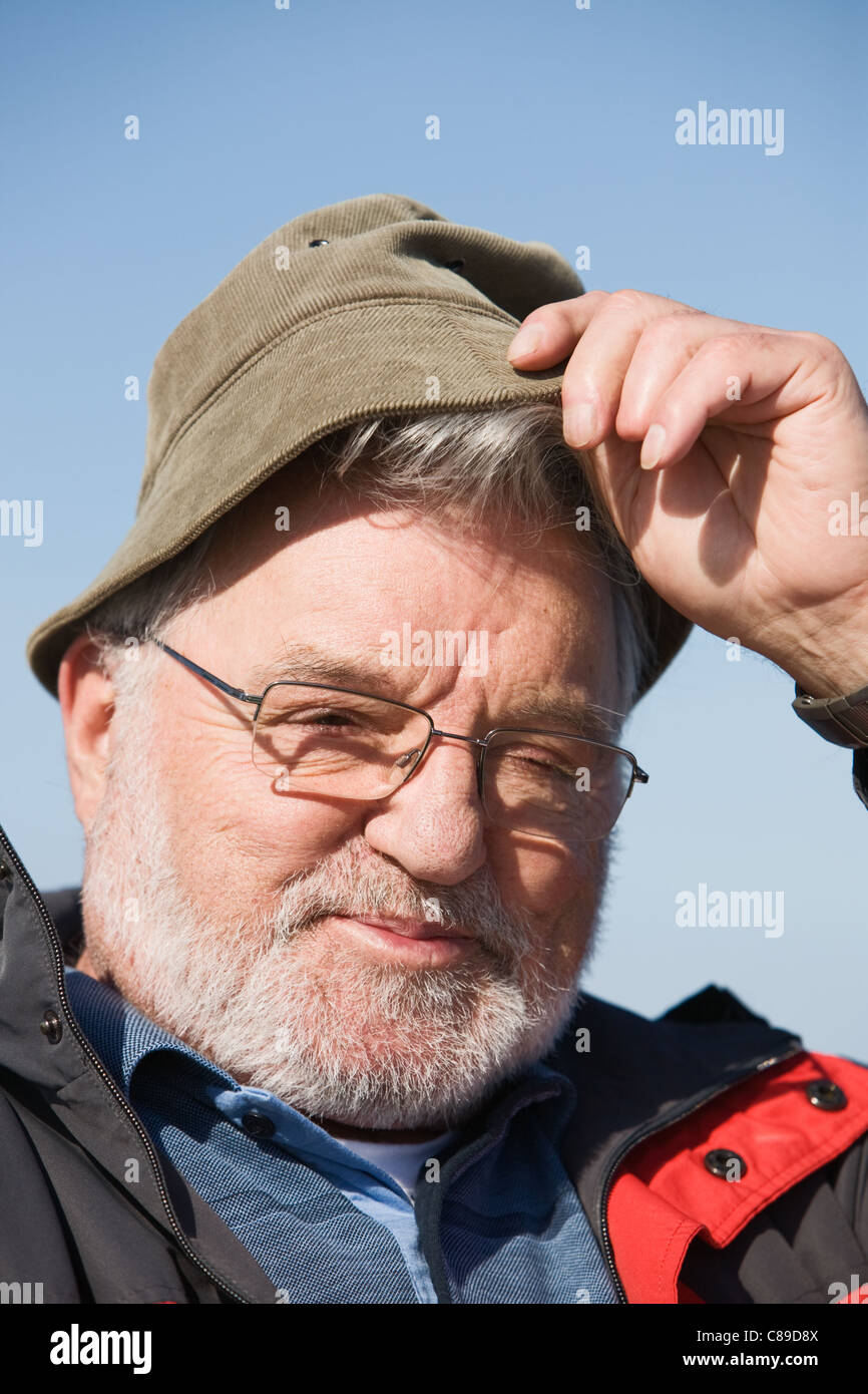 Senior man holding his hat, smiling and winking Stock Photo - Alamy