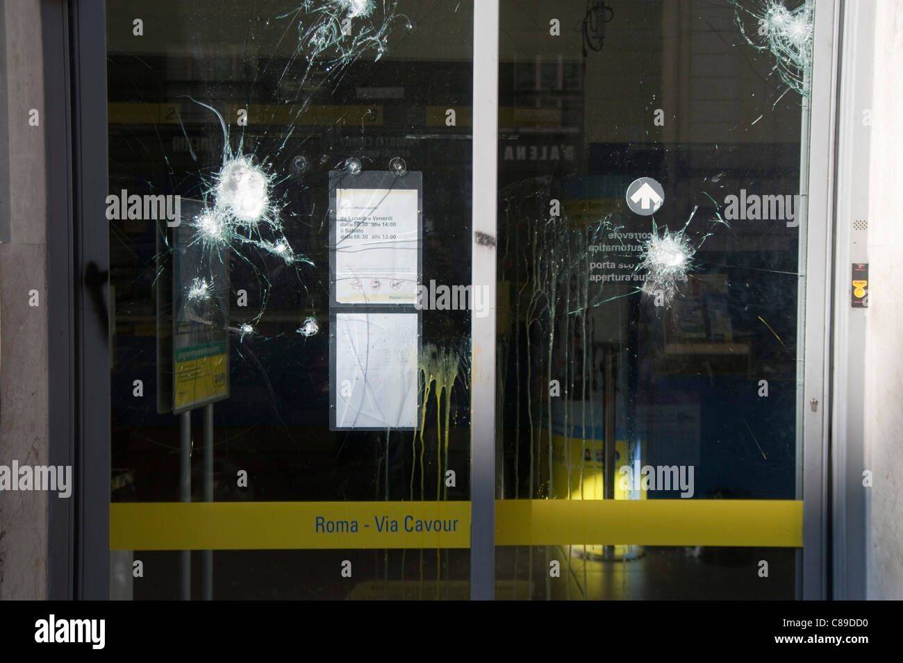 A broken window of Poste italiane and anti government sign are seen ...