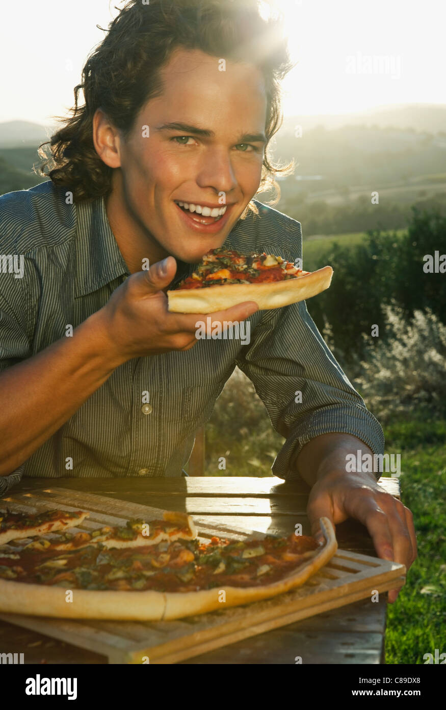 Young man eating pizza at dusk hi-res stock photography and images - Alamy