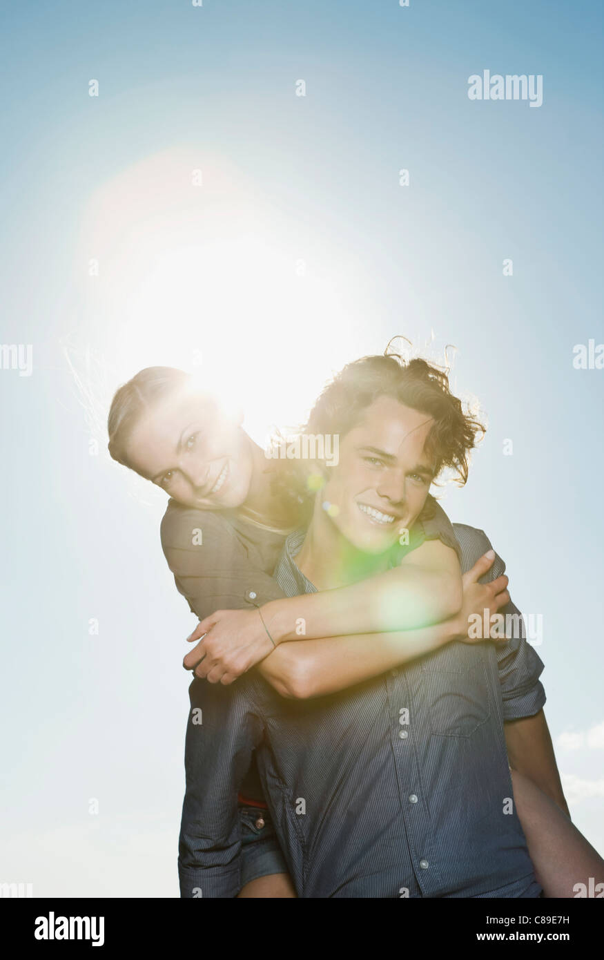 Italy, Tuscany, Young man carrying woman on his back against sun Stock ...