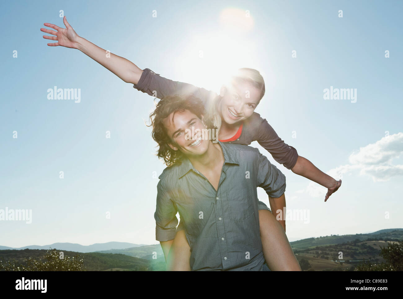 Italy, Tuscany, Young man carrying woman on his back against sun Stock ...