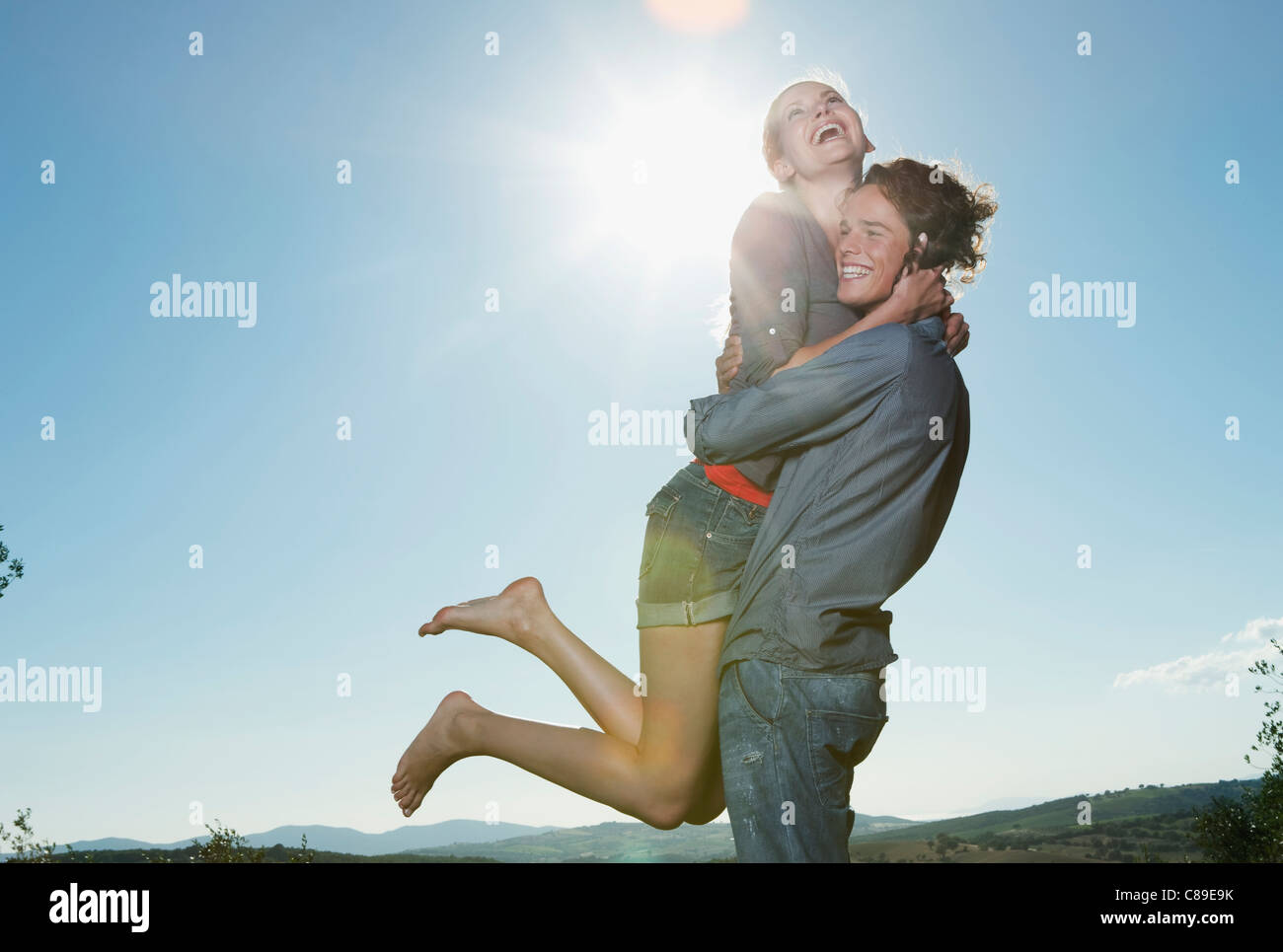 Italy, Tuscany, Young man carrying woman on his back against sun Stock ...