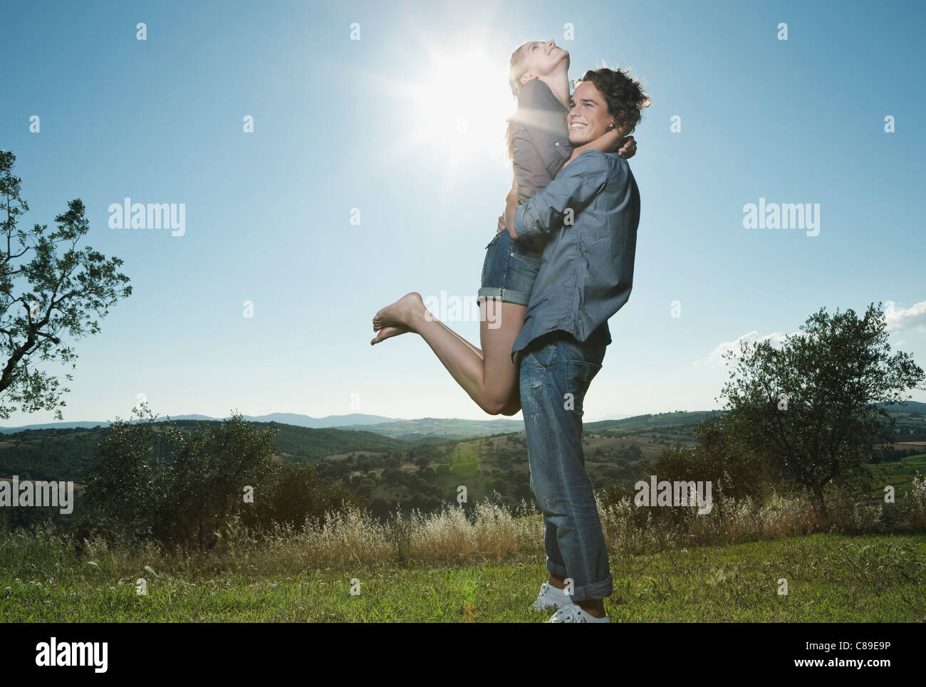 Italy, Tuscany, Young man carrying woman on his back against sun Stock ...