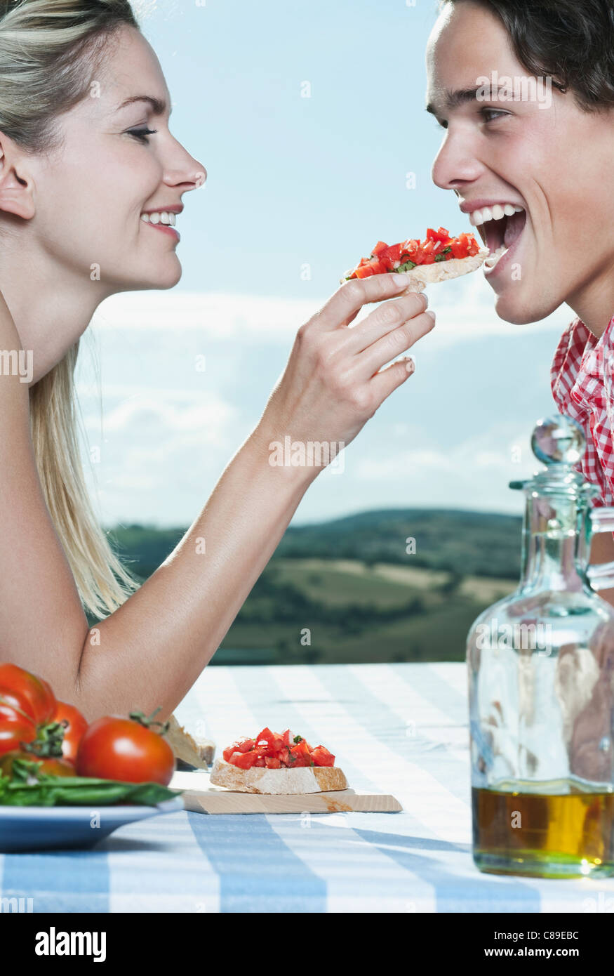 Italy, Tuscany, Young woman feeding snack to man Stock Photo - Alamy