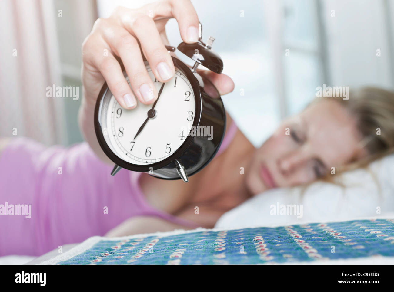 Italy Tuscany Young Woman On Bed Turning Off Alarm Clock In Hotel
