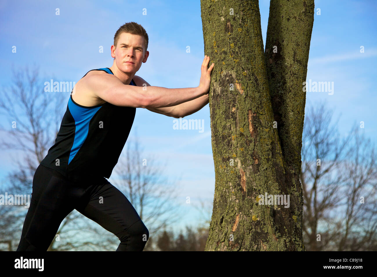 Young man stretching against tree after completing a run Stock Photo ...