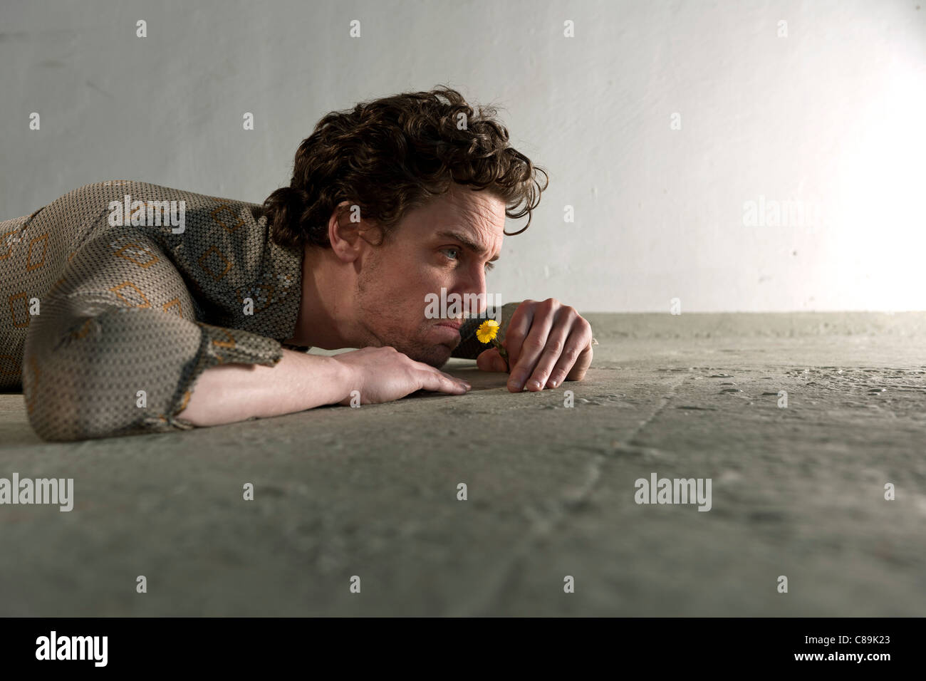 Mid adult man lying on floor and smelling flower Stock Photo - Alamy