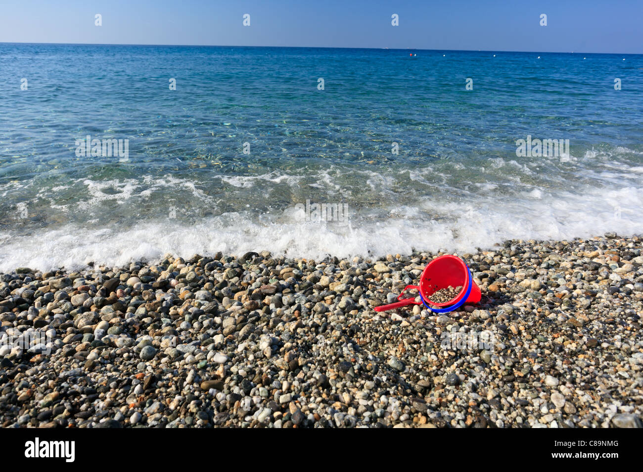 Empty beach with a red bucket left alone Stock Photo - Alamy