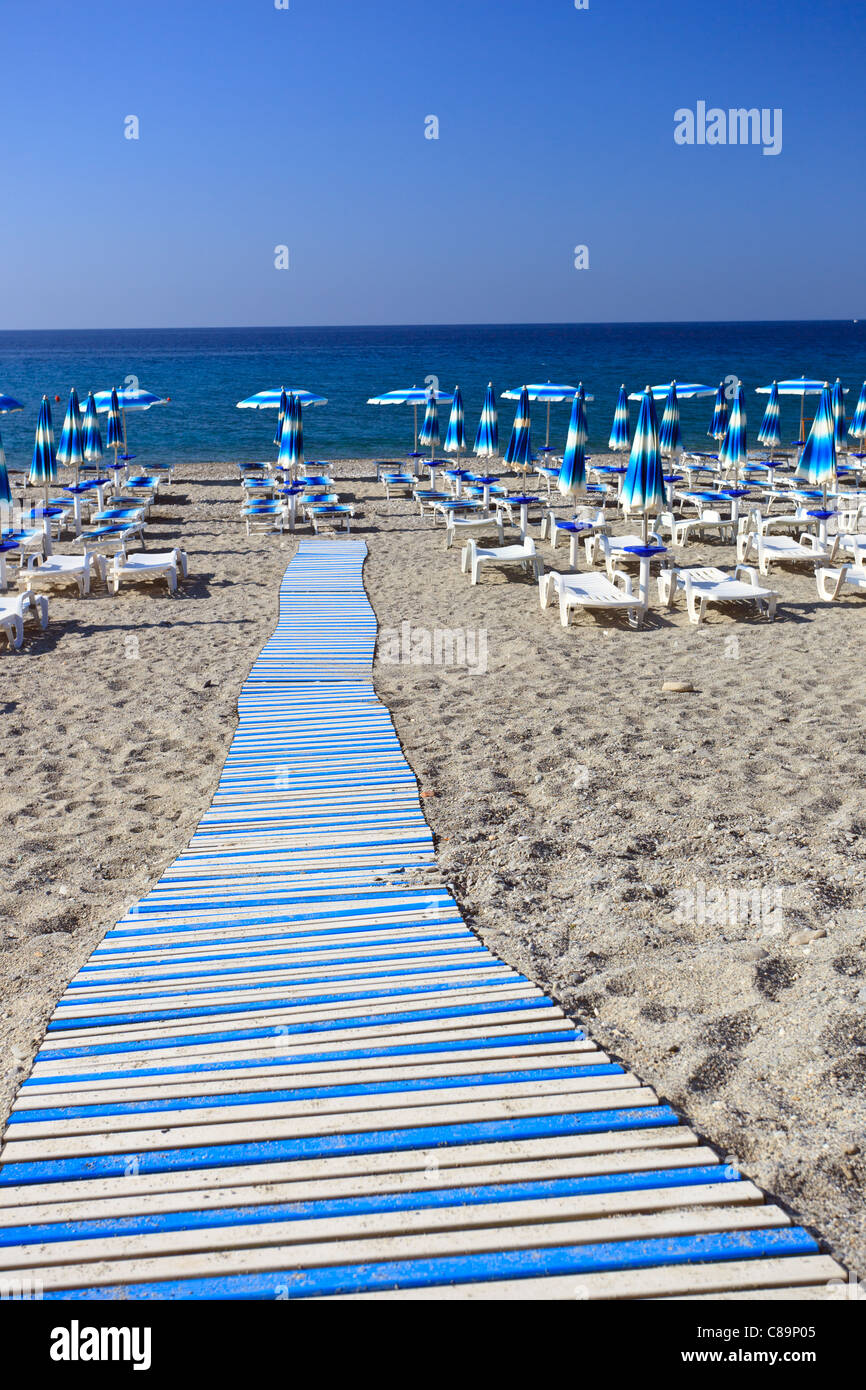 Empty beach with blue umbrellas and welcoming path Stock Photo - Alamy