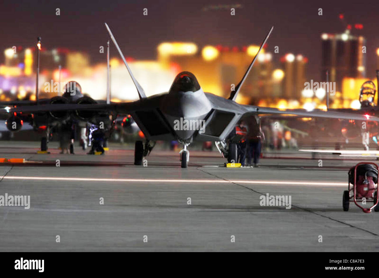 The lights of the Las Vegas Strip shine in the background as an F-22 ...